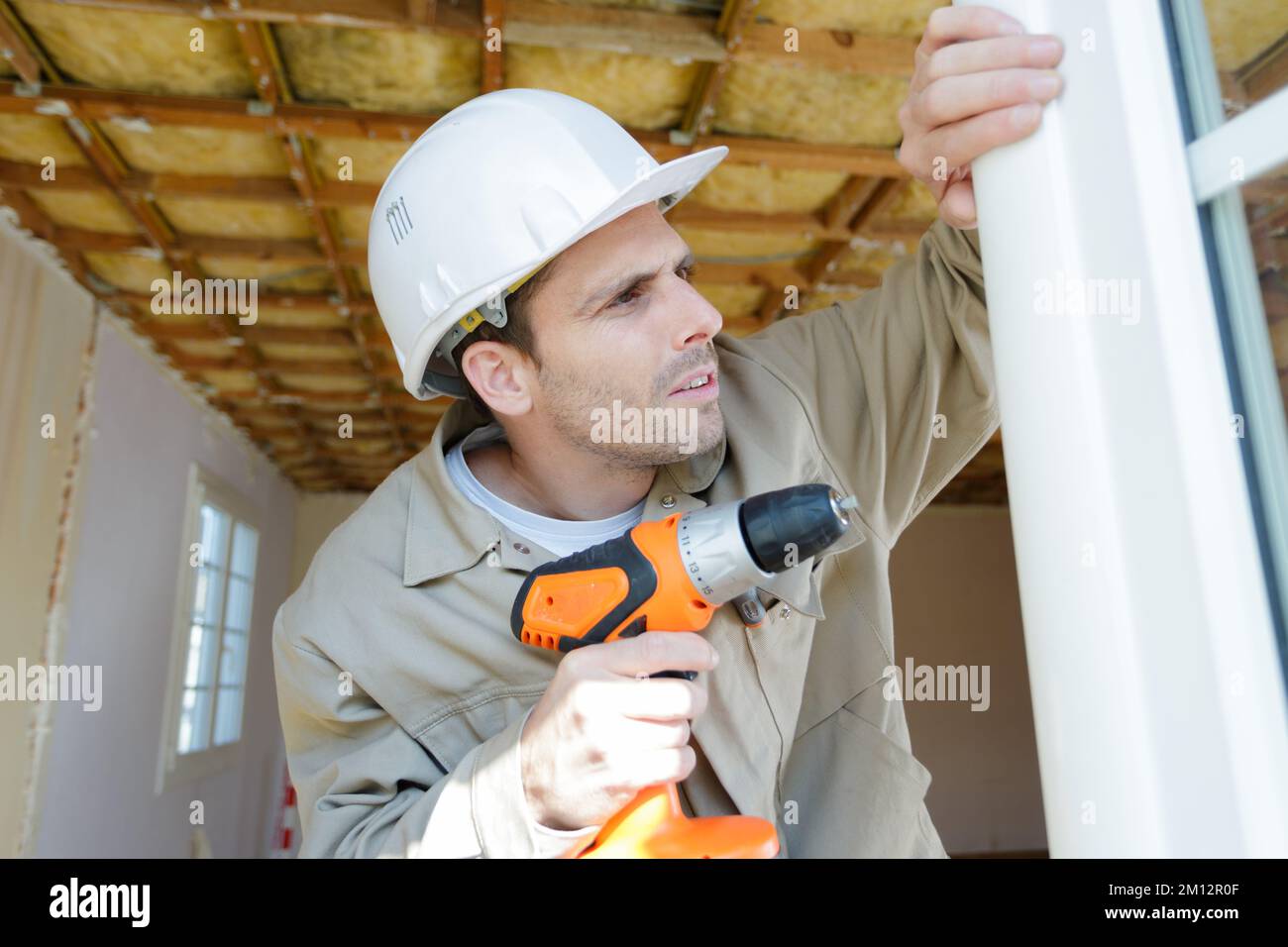 male builder drilling a window Stock Photo - Alamy