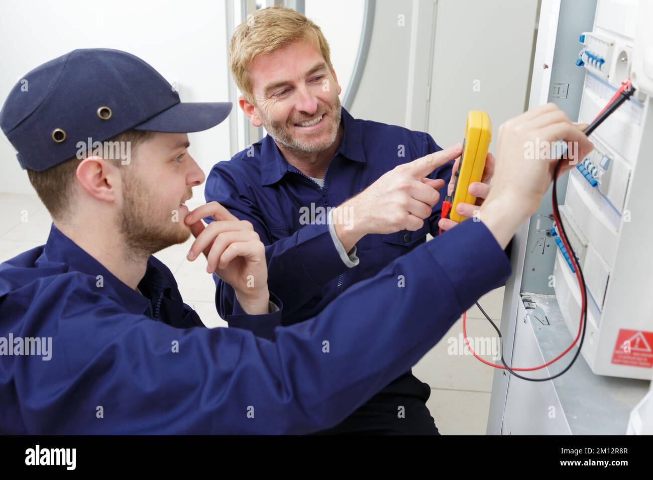 apprentice holding multimeter probes on an electrical panel Stock Photo ...