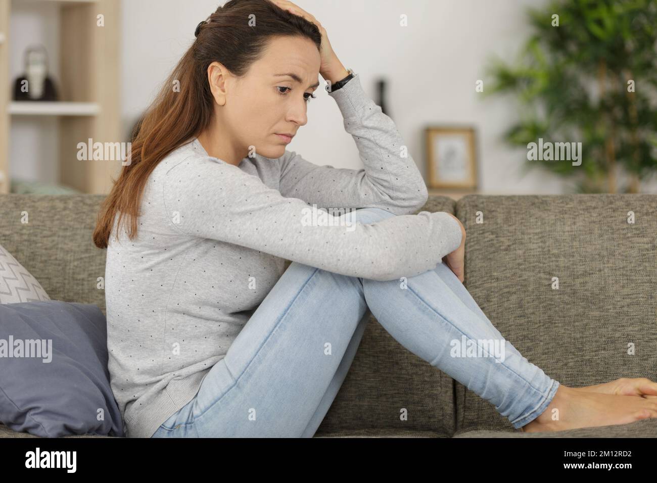 picture of a sad looking woman sitting on the sofa Stock Photo - Alamy