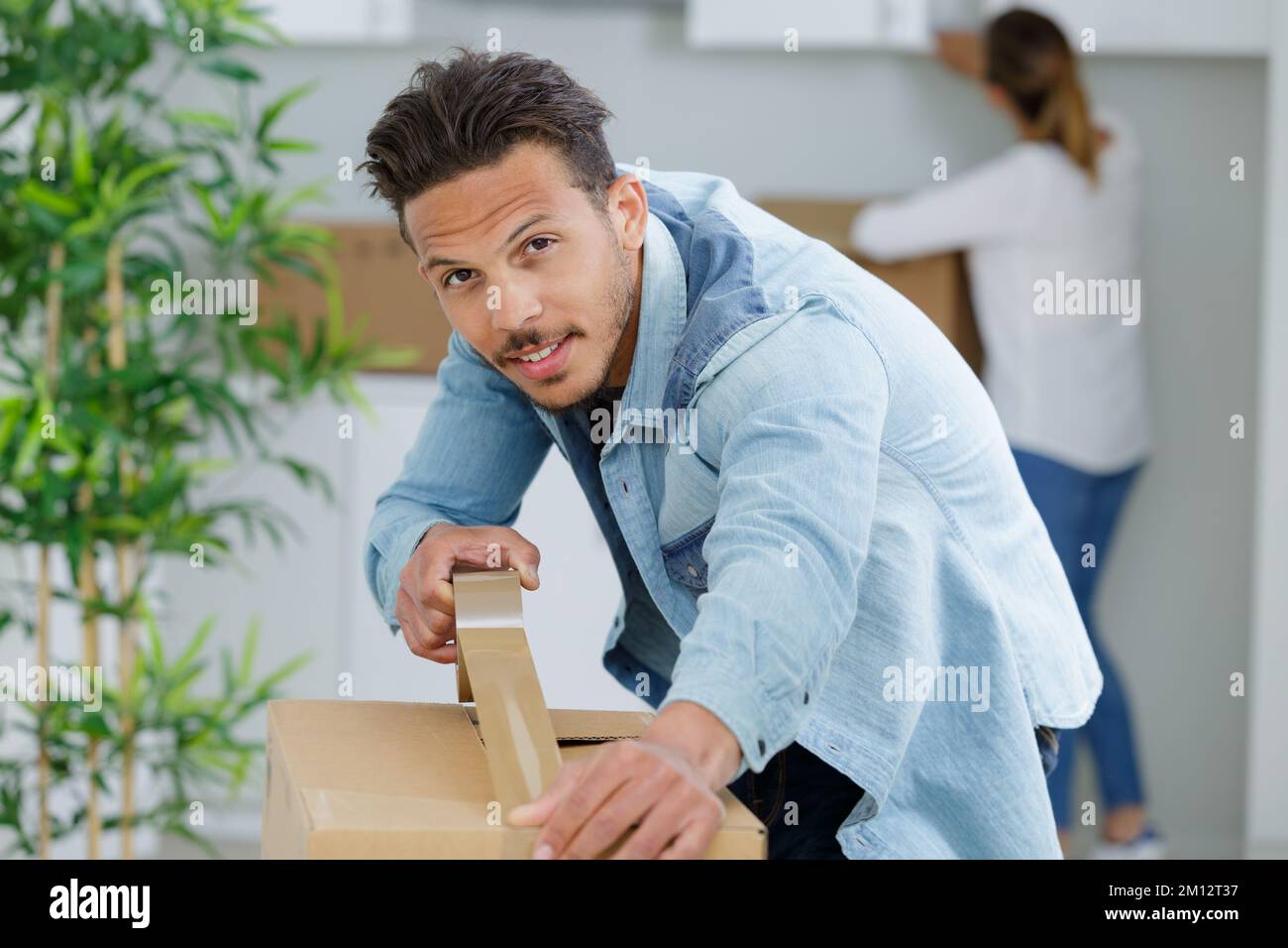 man taping up a cardboard box Stock Photo - Alamy
