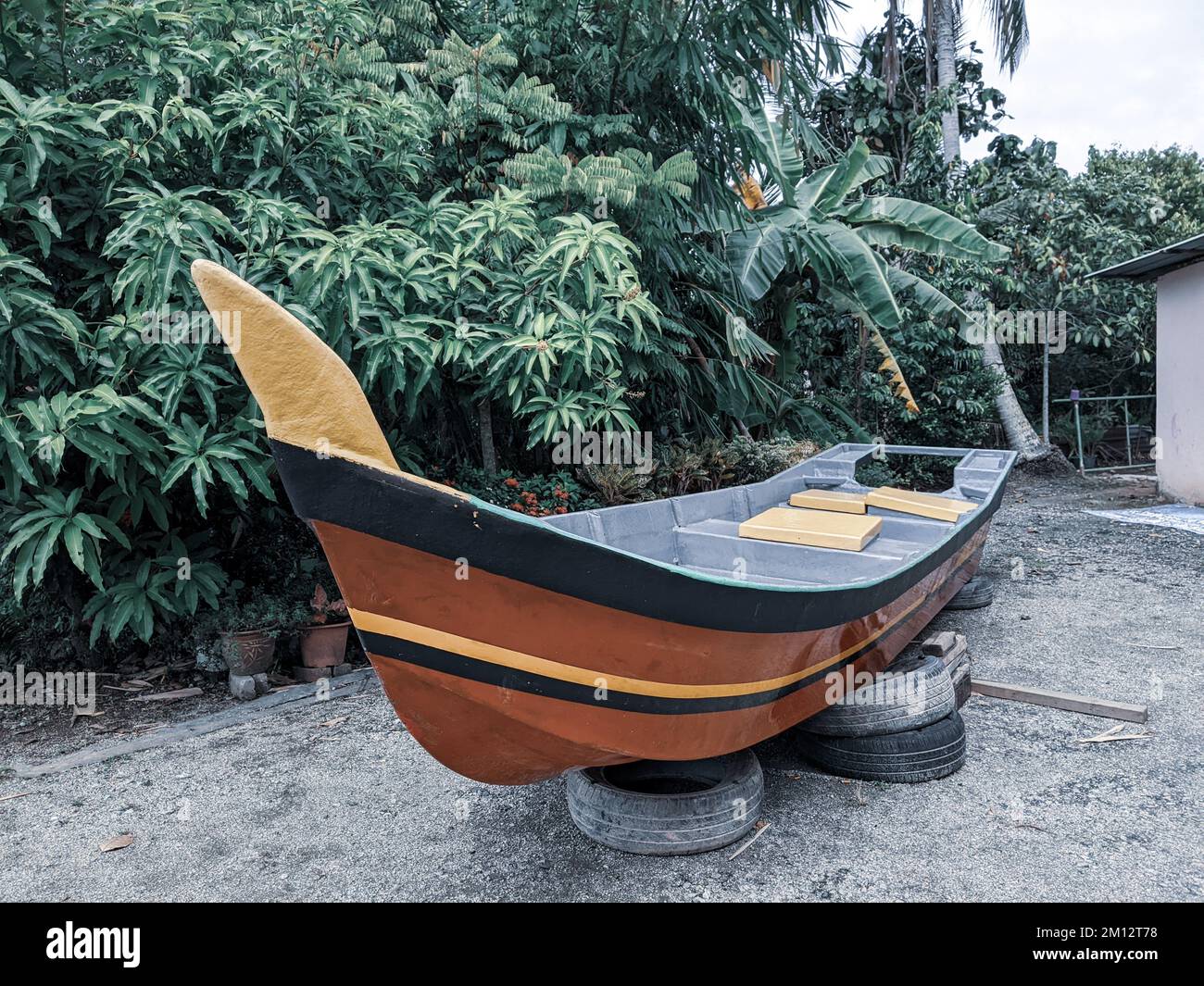 A vintage fishing boat raised on land to be repaired with trees in the ...