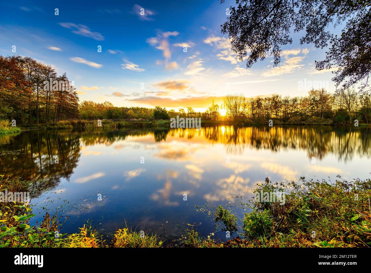 Beautiful sunrise at the lake with reflection in the water and clouds ...