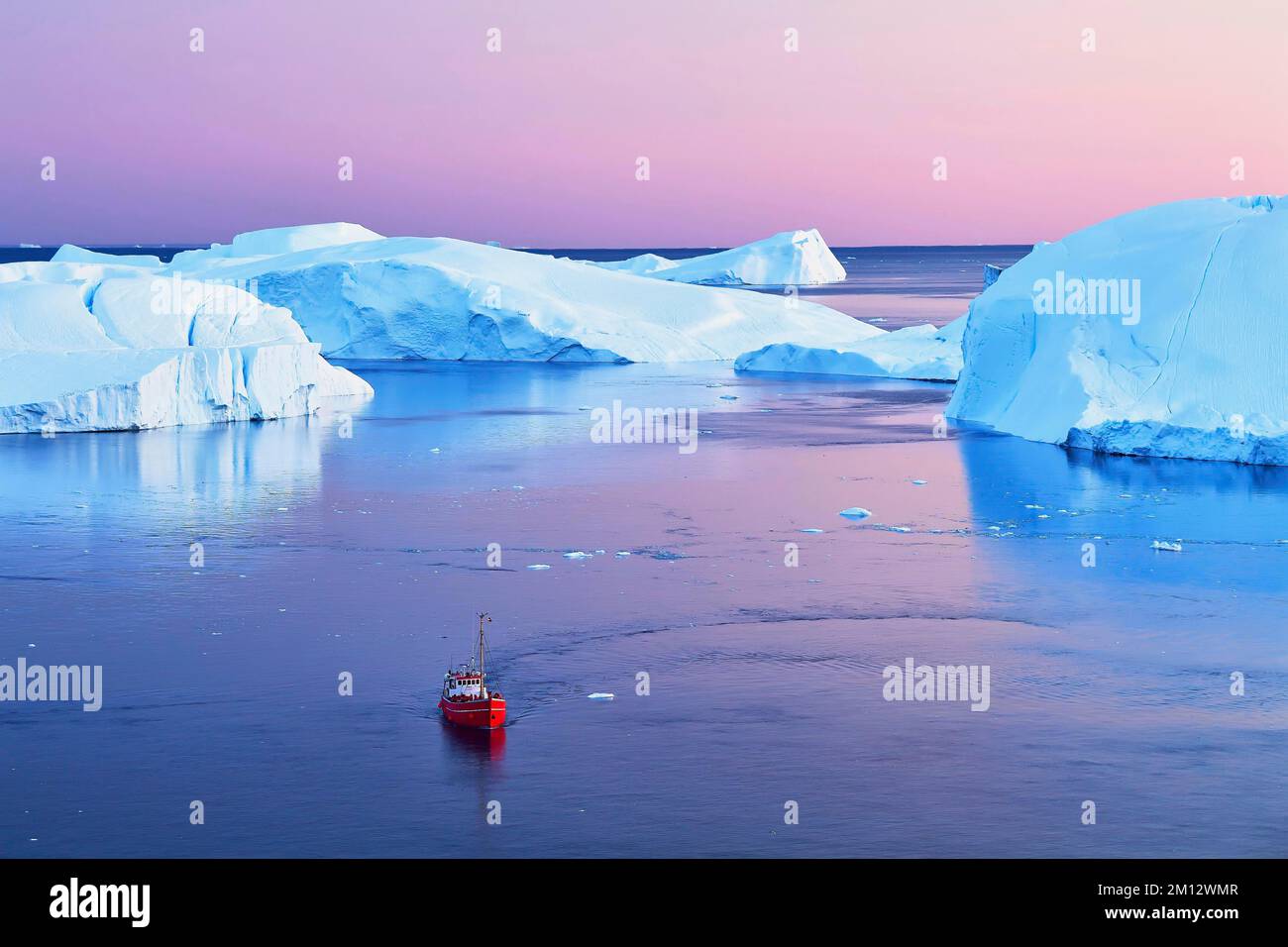 Red boat with tourists in front of icebergs at blue hour, Icefjord ...