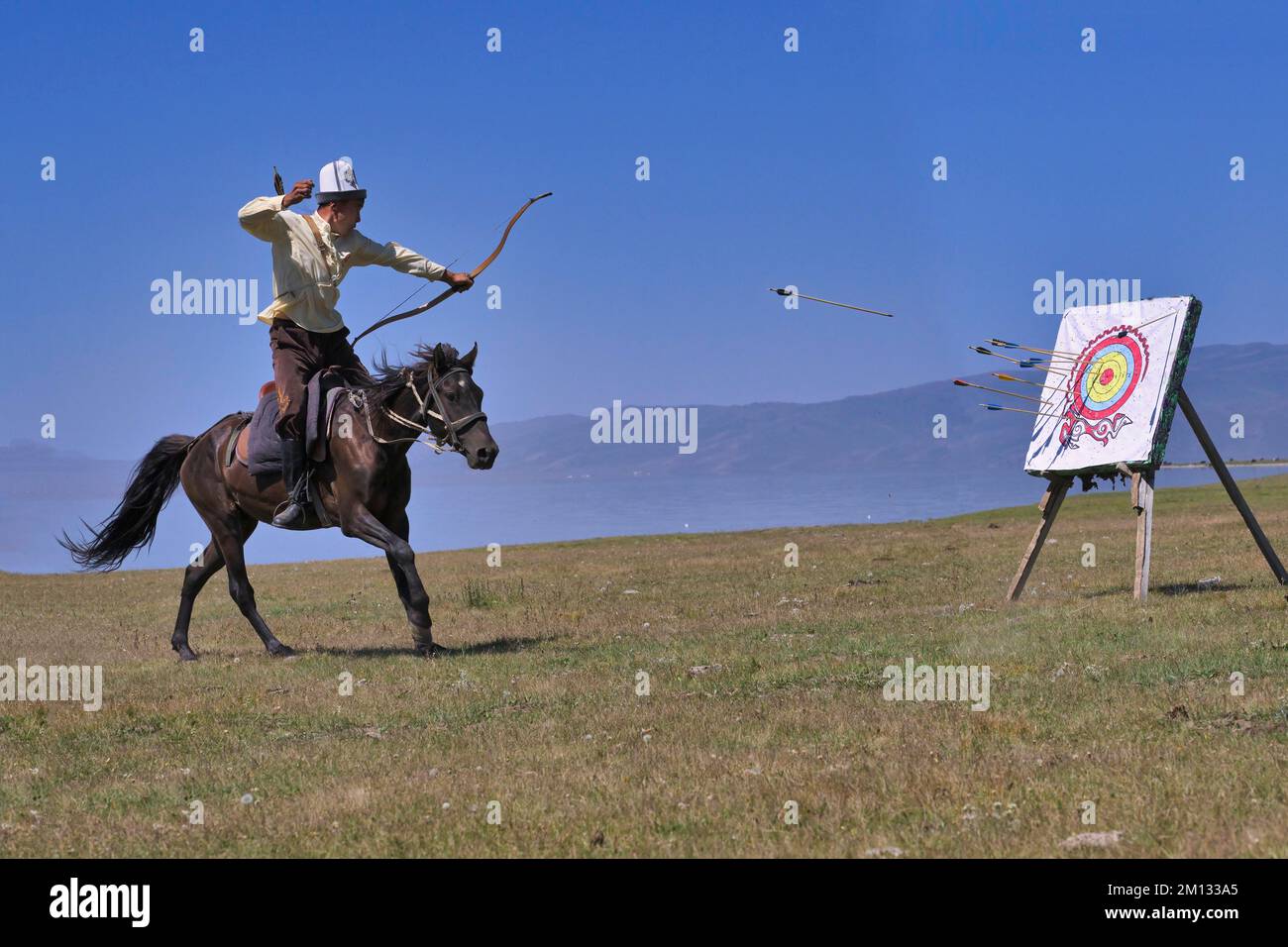 Kyrgyz nomad shooting arrows on a target while galloping, Song kol lake ...