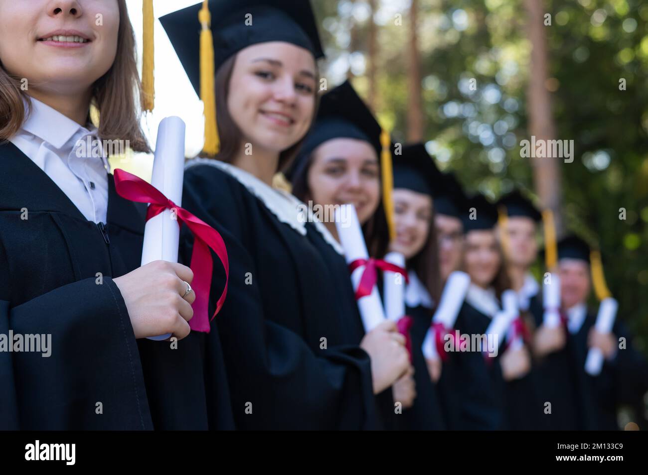 Row of young people in graduation gowns outdoors. Age student Stock ...