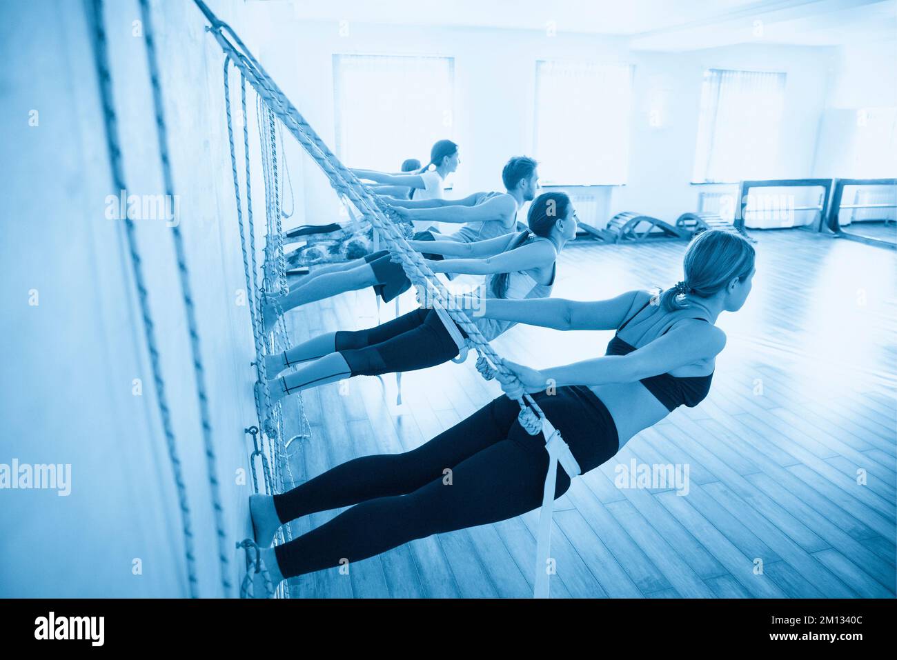 People hanging on ropes practicing yoga stretching in gym. Fit and ...