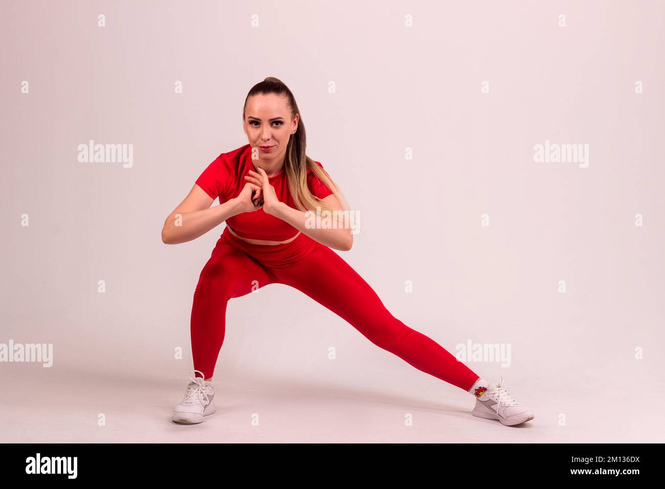 A young woman in a red tracksuit goes in for sports on a white ...