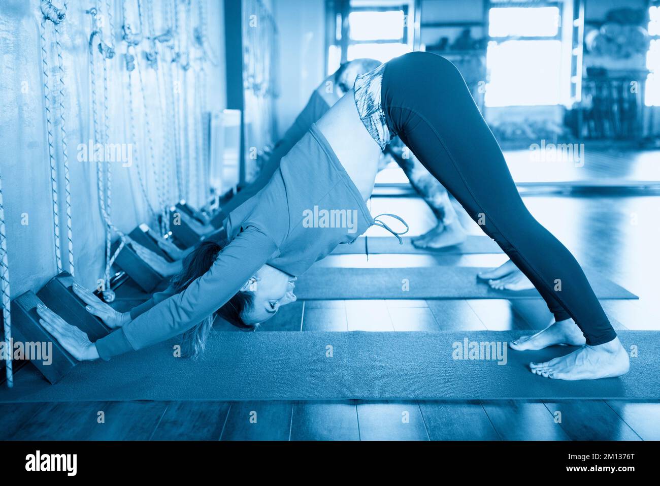 Women practicing yoga stretching using wooden blocks with hands ...
