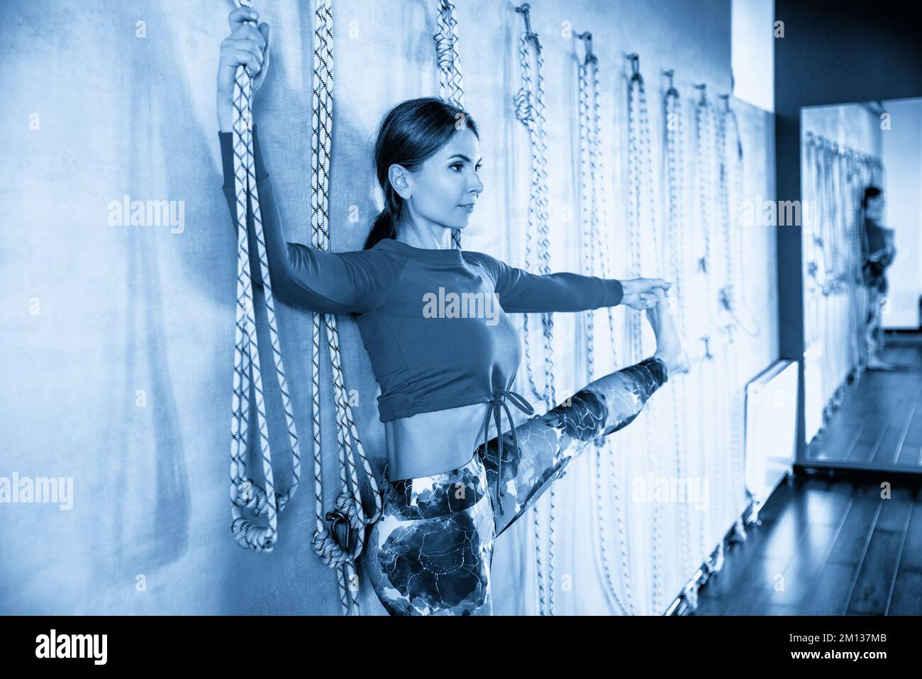 Young girl doing yoga pose with rope against wall Stock Photo - Alamy