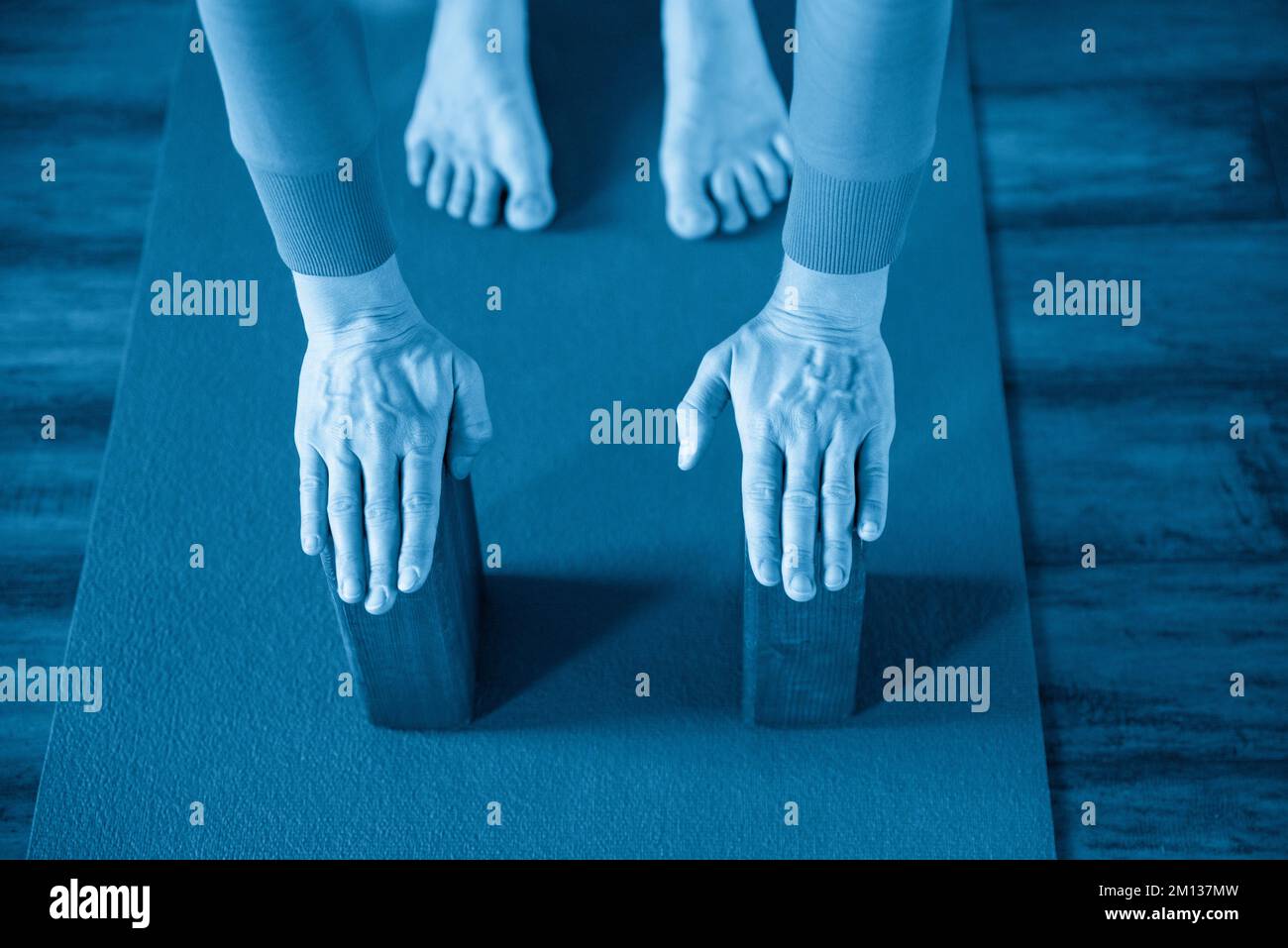 Women practicing yoga stretching using wooden blocks with hands ...