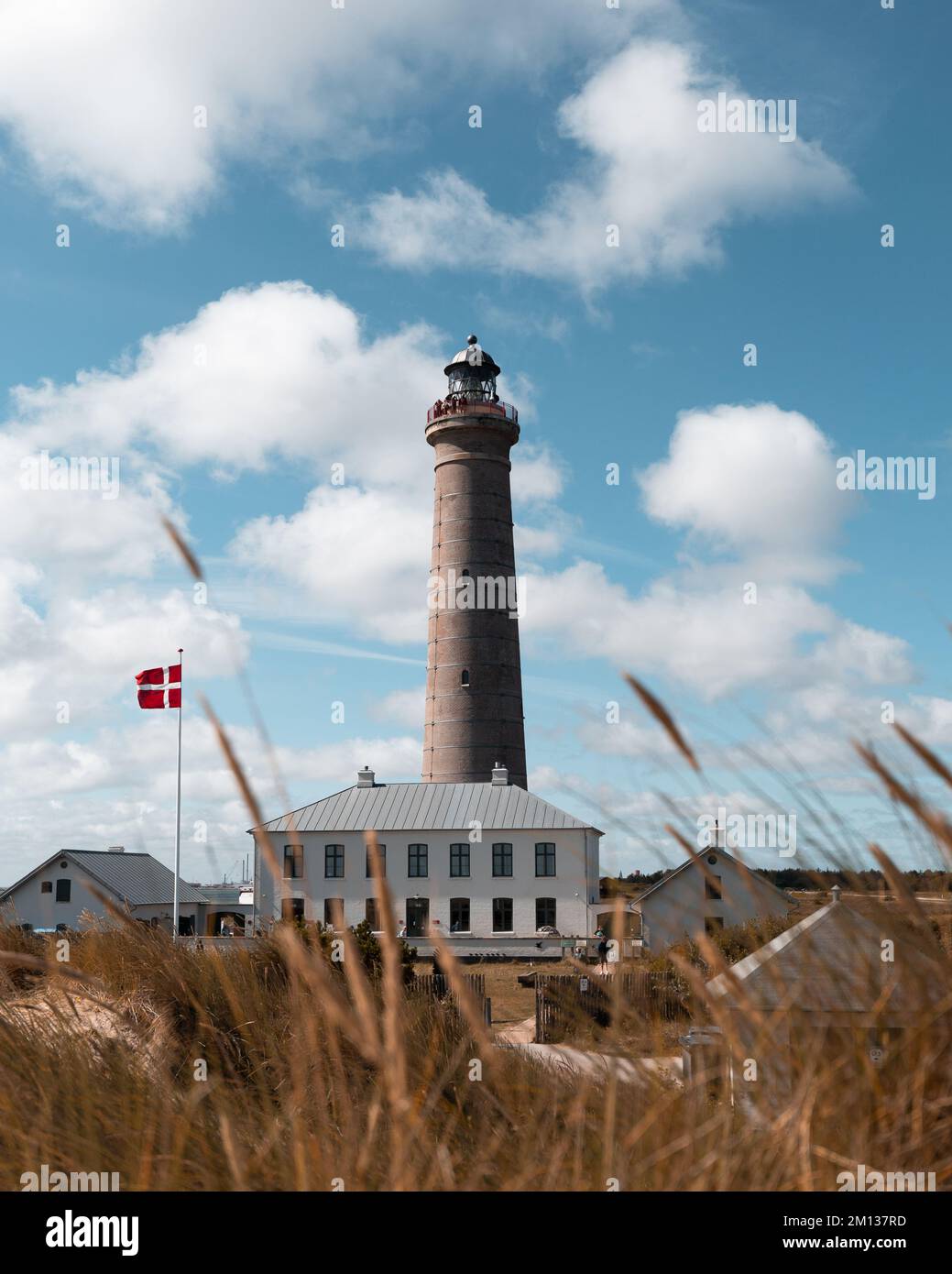 The Danish flag waving in front of the Skagen Lighthouse under blue ...