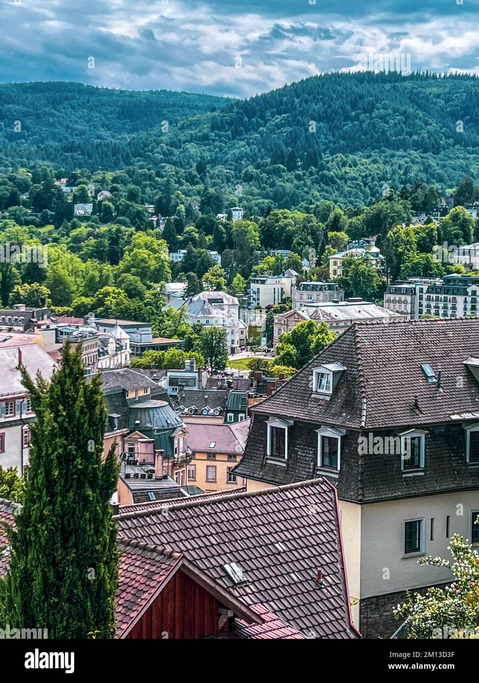 A vertical shot of a townscape with a background of green forested ...