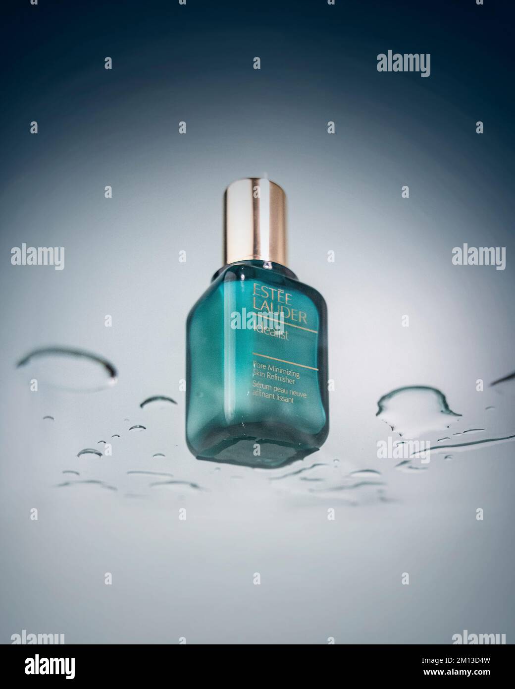 A vertical shot of an Estee Lauder skin serum on a wet glass surface ...