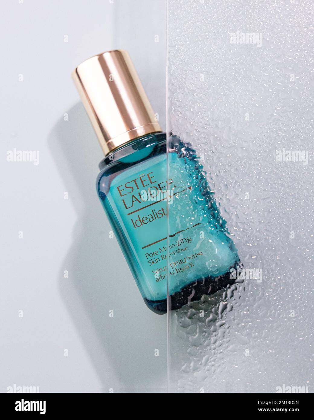 A vertical shot of an Estee Lauder skin serum with a wet glass surface ...