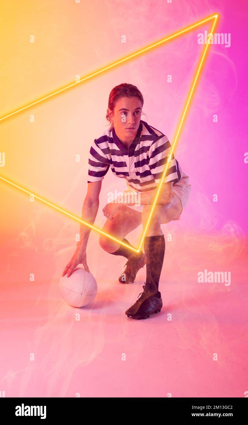 Caucasian female rugby player with ball crouching by illuminated ...