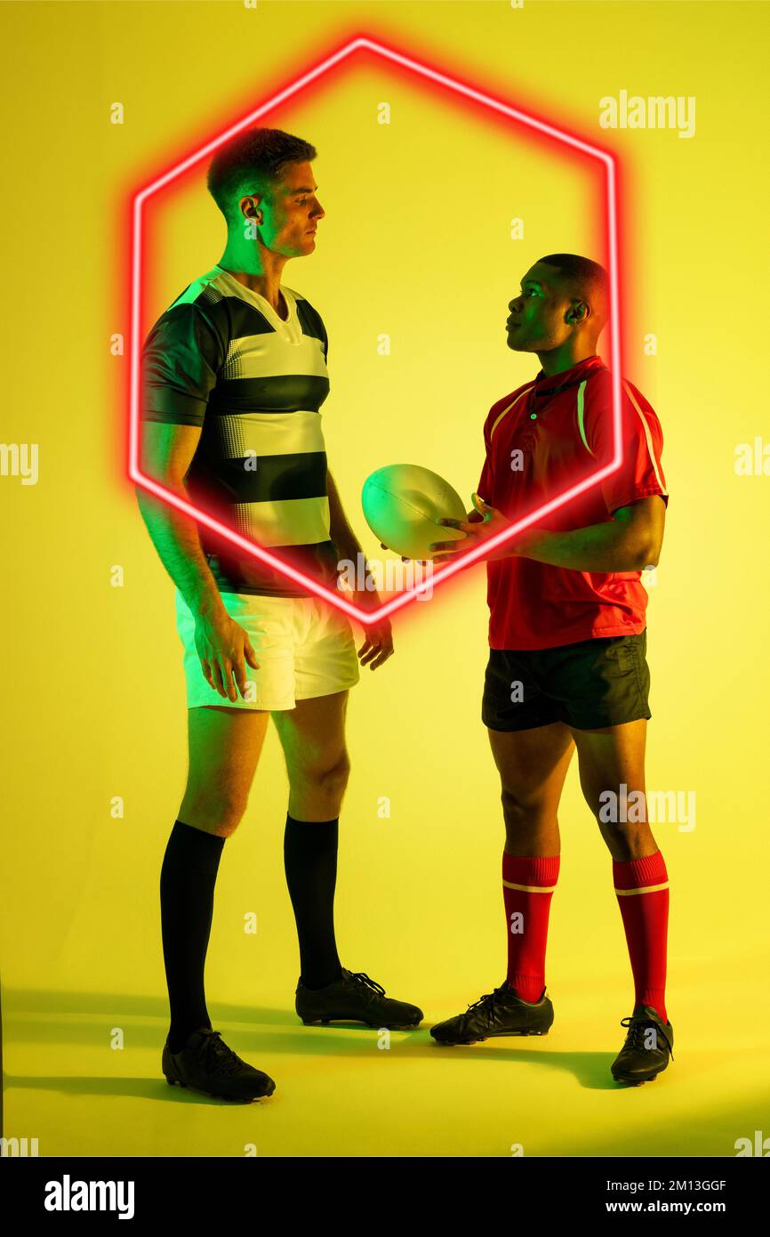 Multiracial male rugby opponents staring at each other by glowing ...