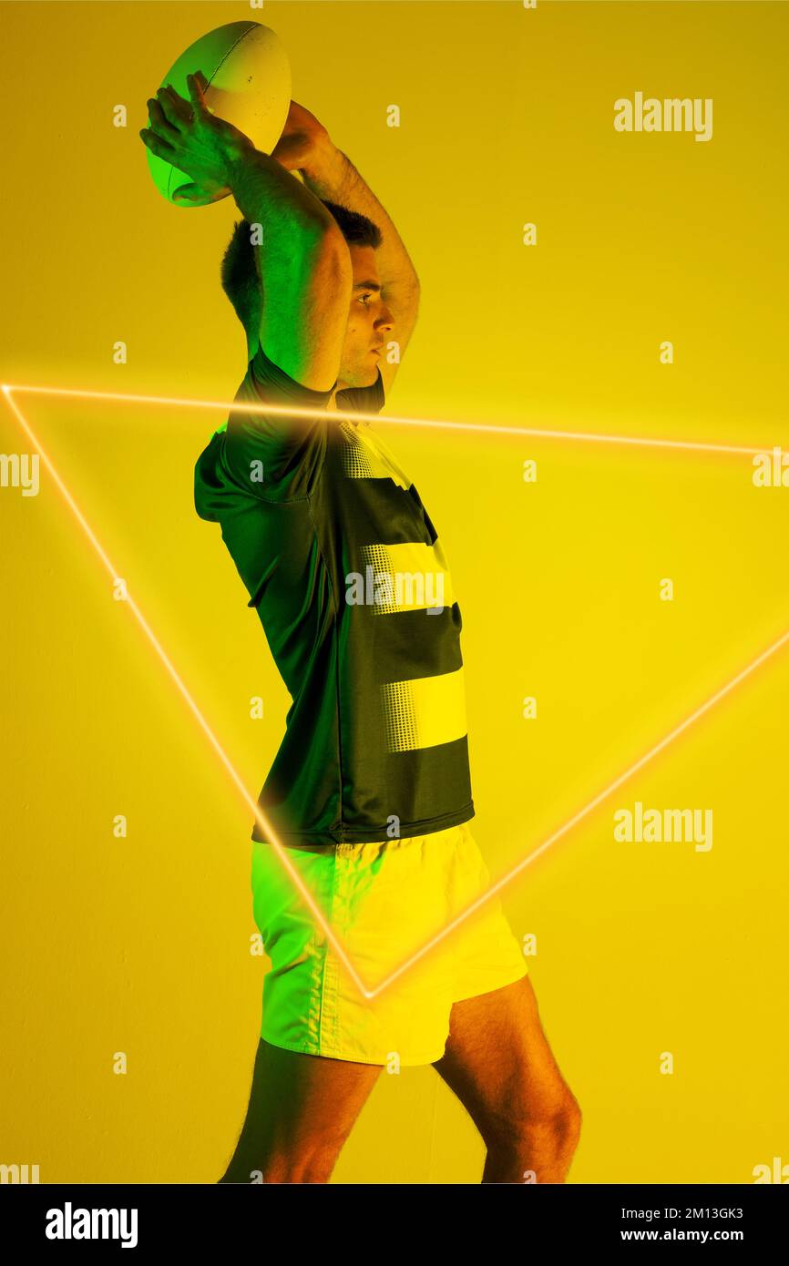 Side view of caucasian male rugby player throwing ball by illuminated ...