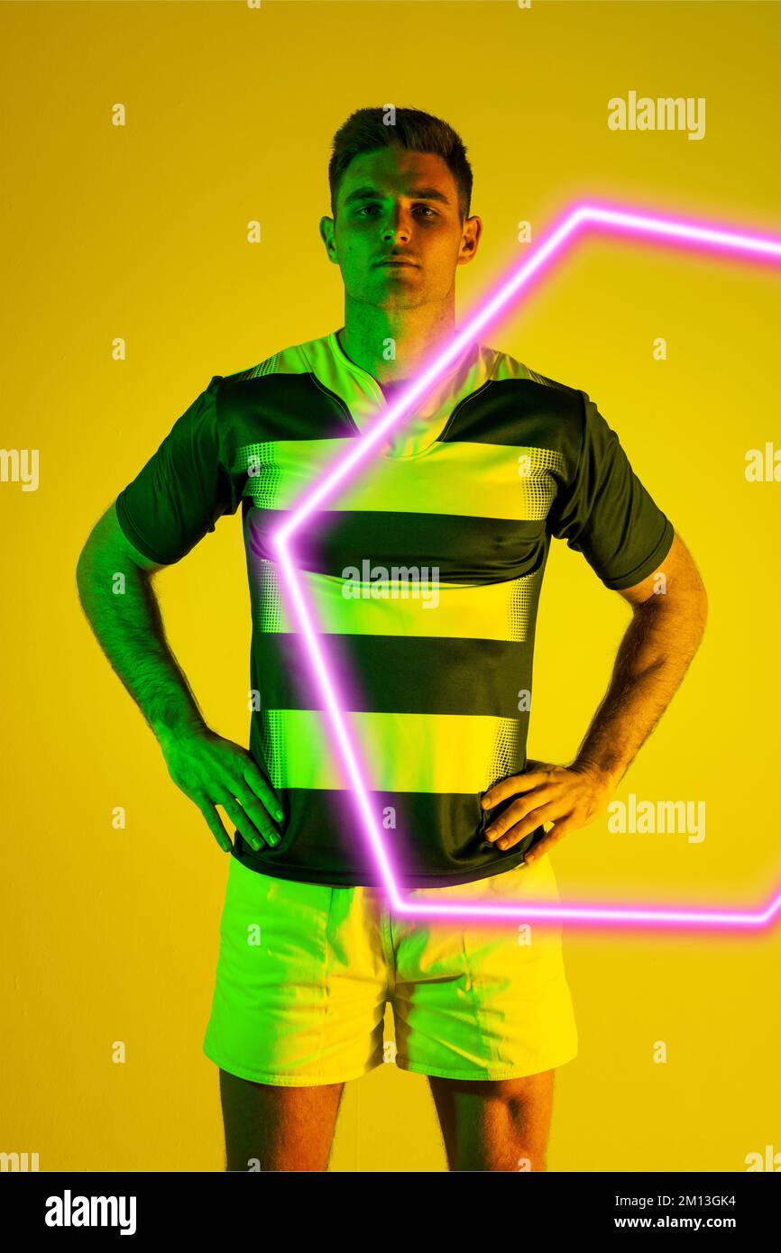 Confident male caucasian rugby player with hands on hip by illuminated ...