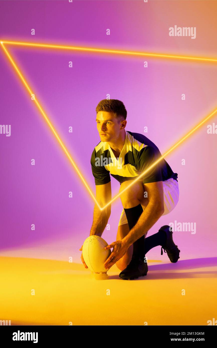 Caucasian male rugby player placing ball on stand by illuminated ...