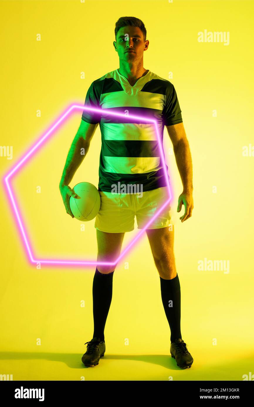 Serious male caucasian rugby player with ball by illuminated triangle ...