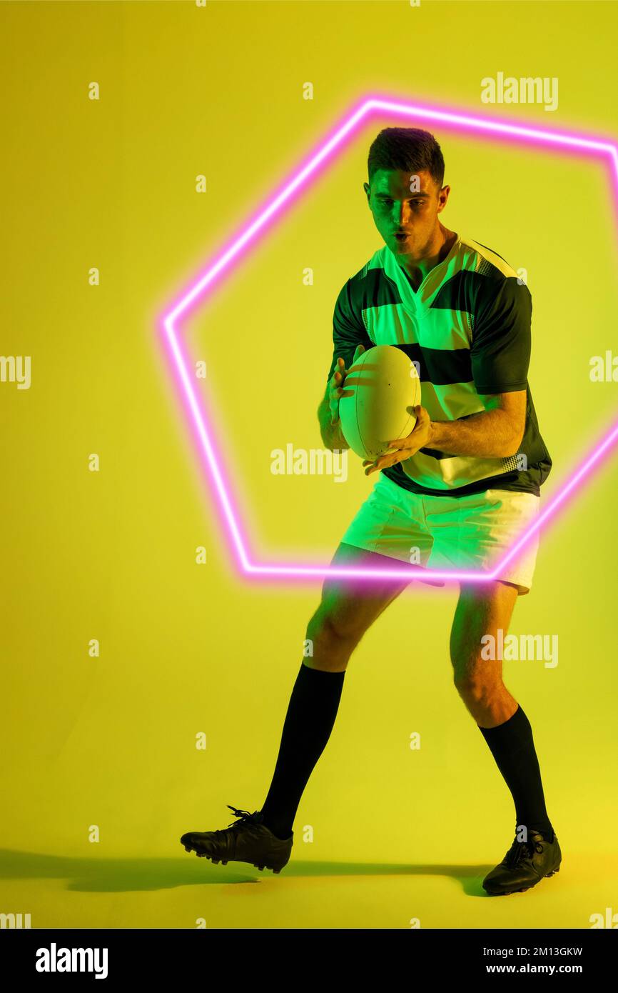 Full length of caucasian male rugby player with ball by illuminated ...
