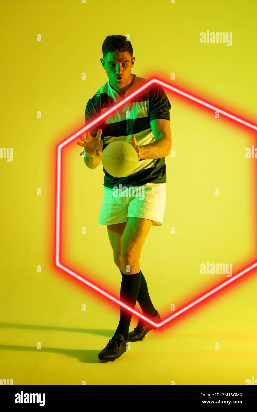 Male caucasian rugby player catching ball by illuminated hexagon over ...