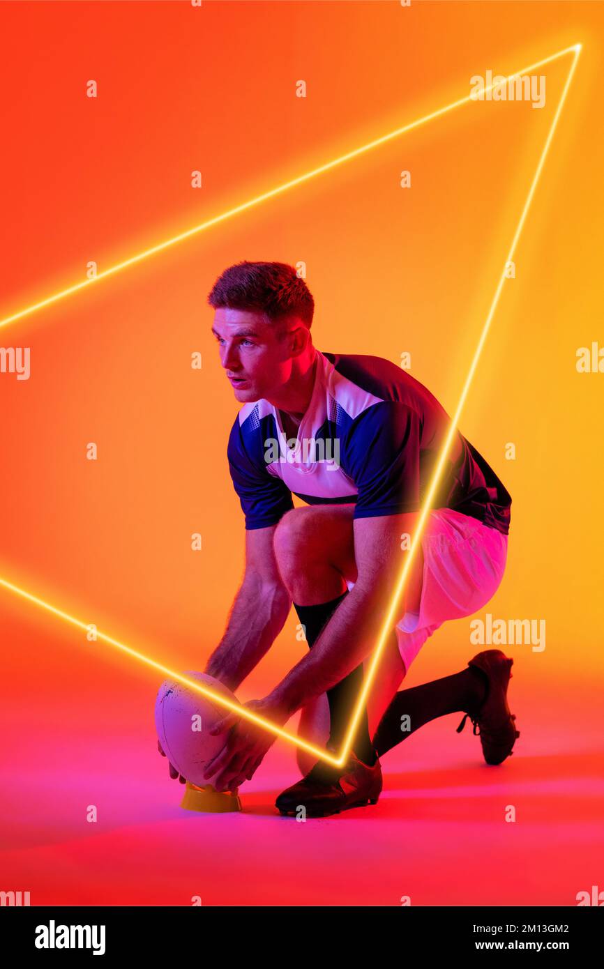 Caucasian male player placing rugby ball on stand by illuminated ...