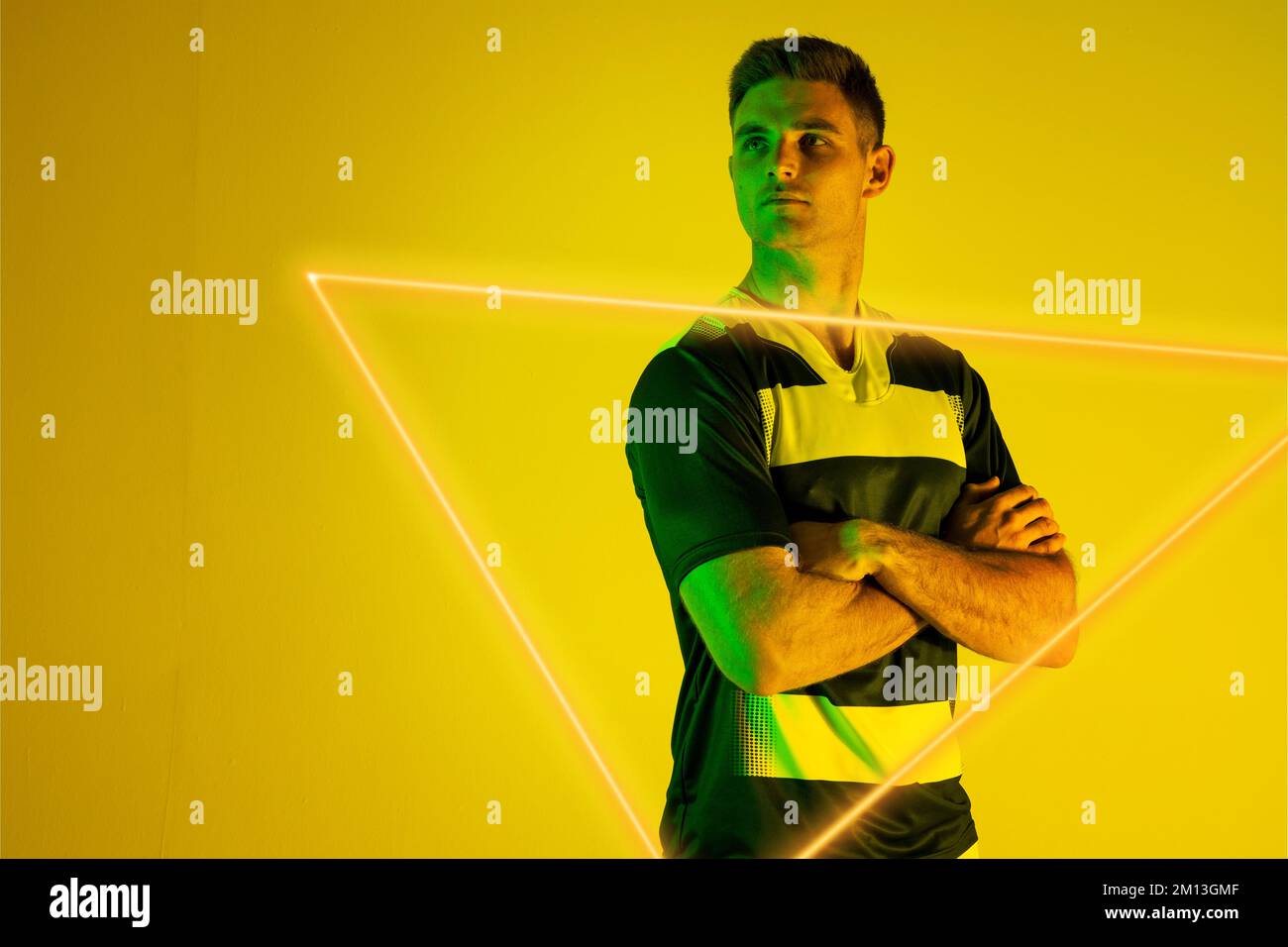 Male caucasian rugby player with arms crossed standing by illuminated ...