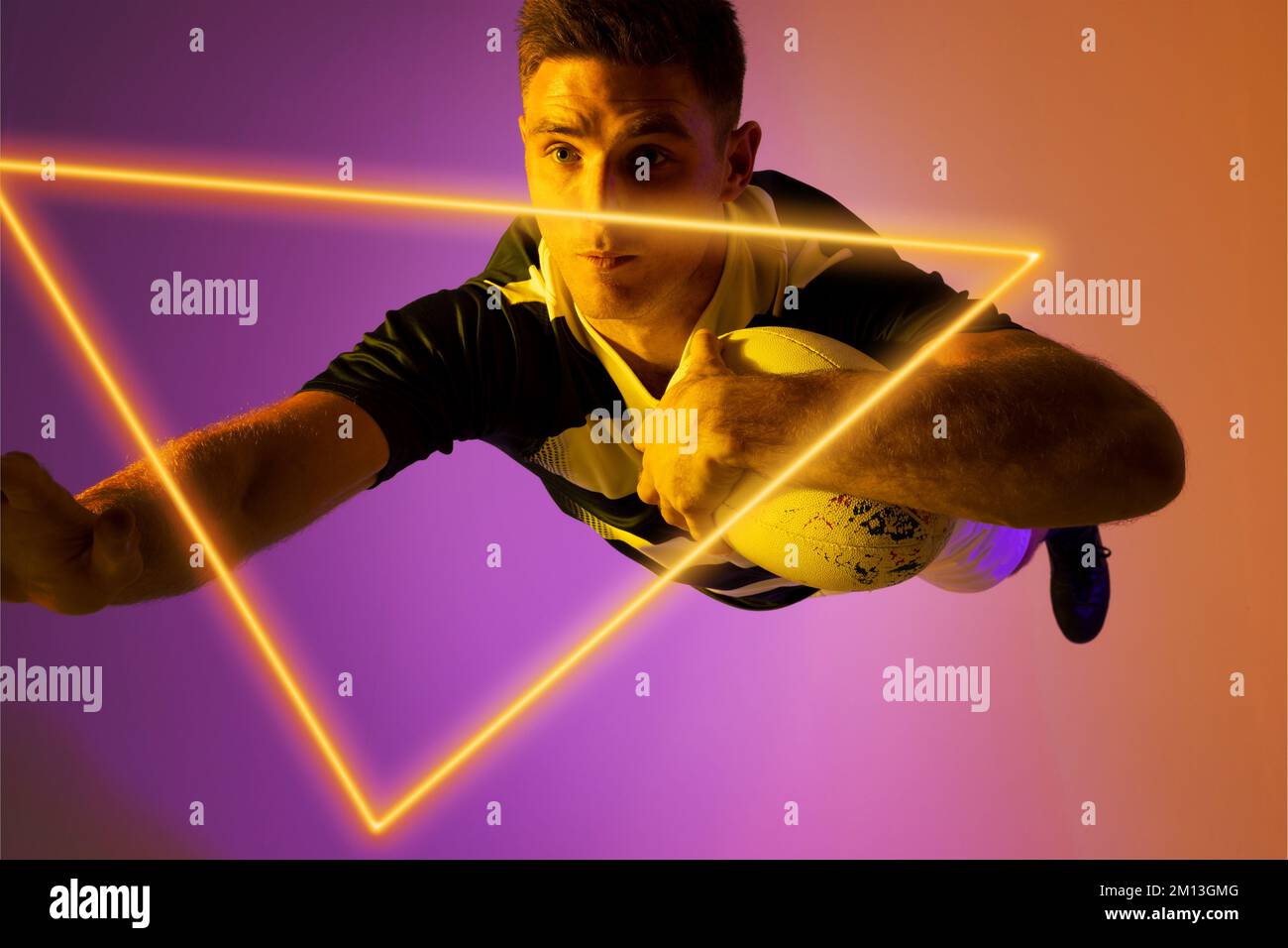 Caucasian male rugby player with ball jumping by illuminated triangle ...