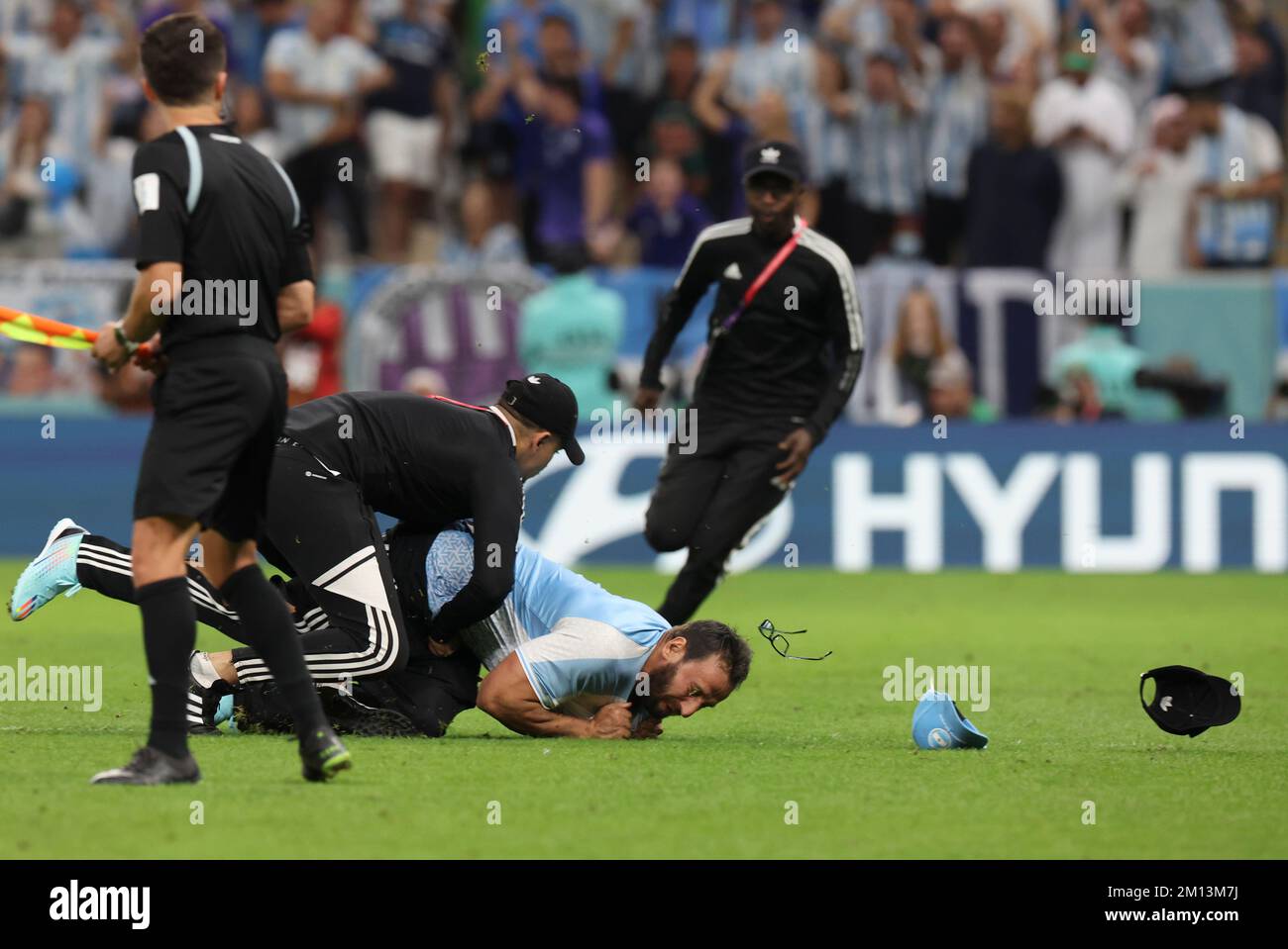 Lusail, Qatar. 9th Dec, 2022. A pitch invader (2nd R) is tackled by ...