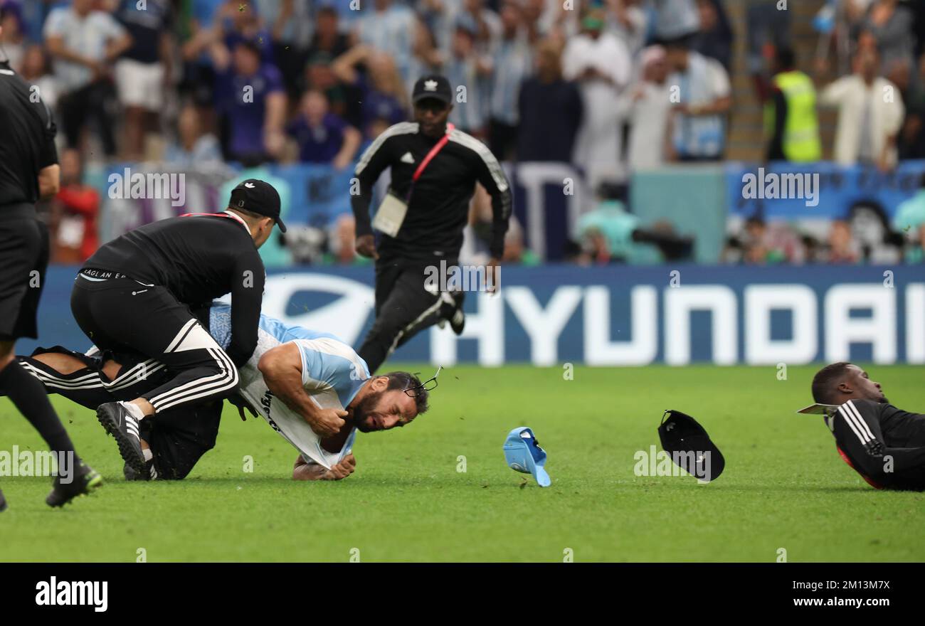Lusail, Qatar. 9th Dec, 2022. A pitch invader (C) is tackled by staff ...