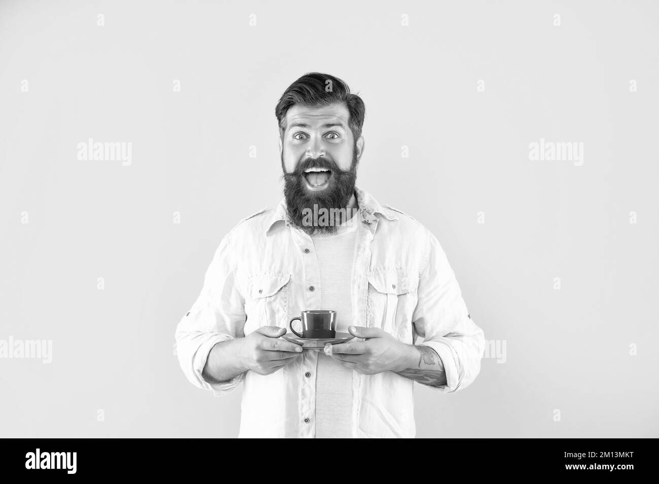amazed cheerful hipster with beard holding coffee cup on yellow ...