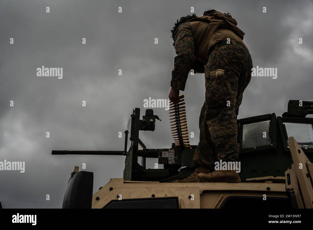 A U.S. Marine machine gunner with 3rd Battalion, 4th Marines, loads .50 ...