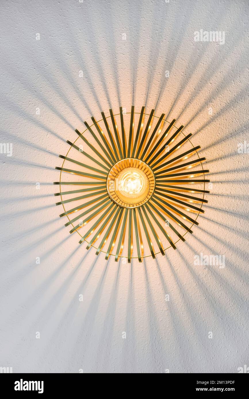 a wall light in the shape of a sunbursting on a white wall, with ...