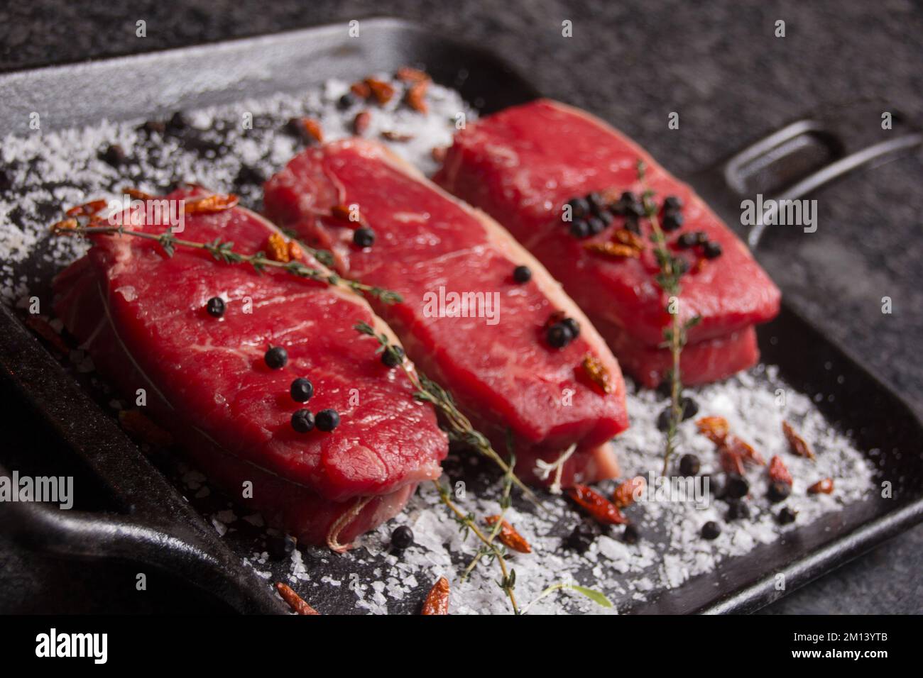 Raw steak seasoned on a cast iron pan Stock Photo - Alamy