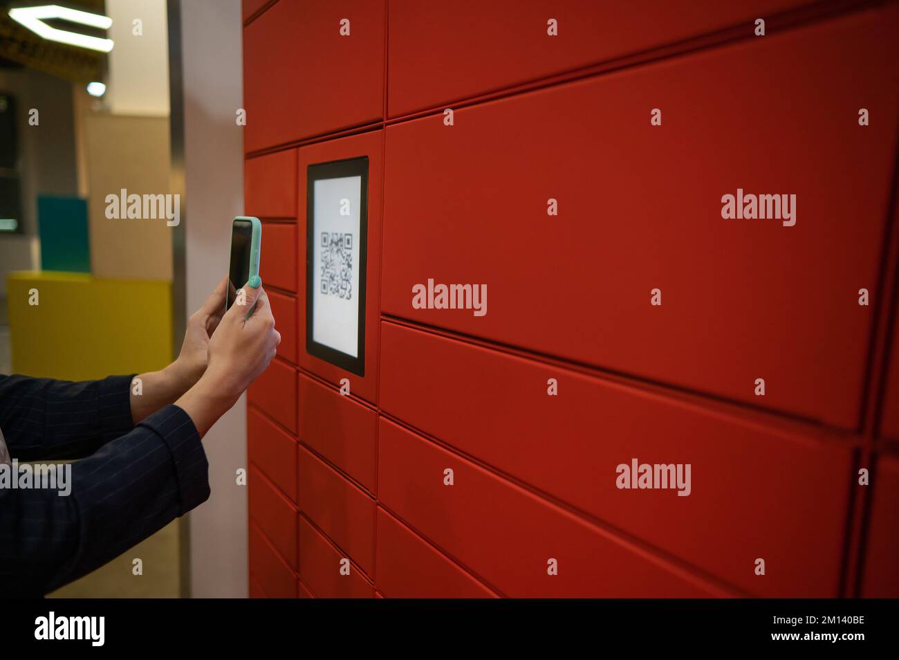 A woman scans a red code to pick up a parcel at a parcel machine ...