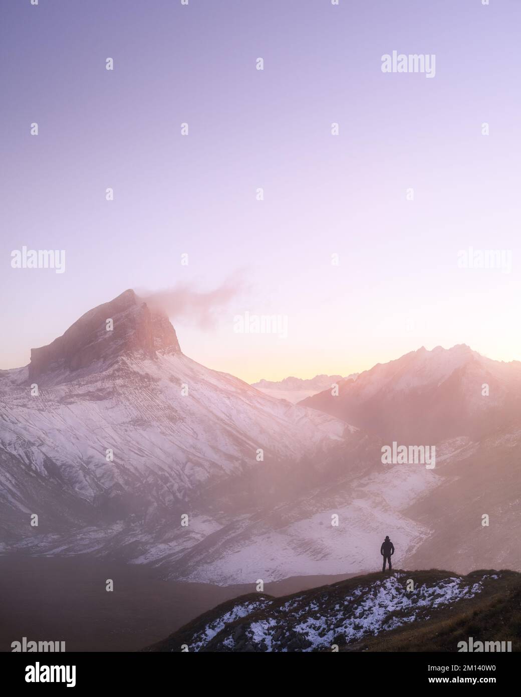 A vertical shot of a man silhouette in front of a foggy and snowy ...