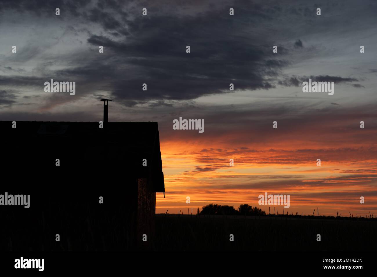 Rustic barn silhouette under a sunset sky prairie landscape in Rocky ...