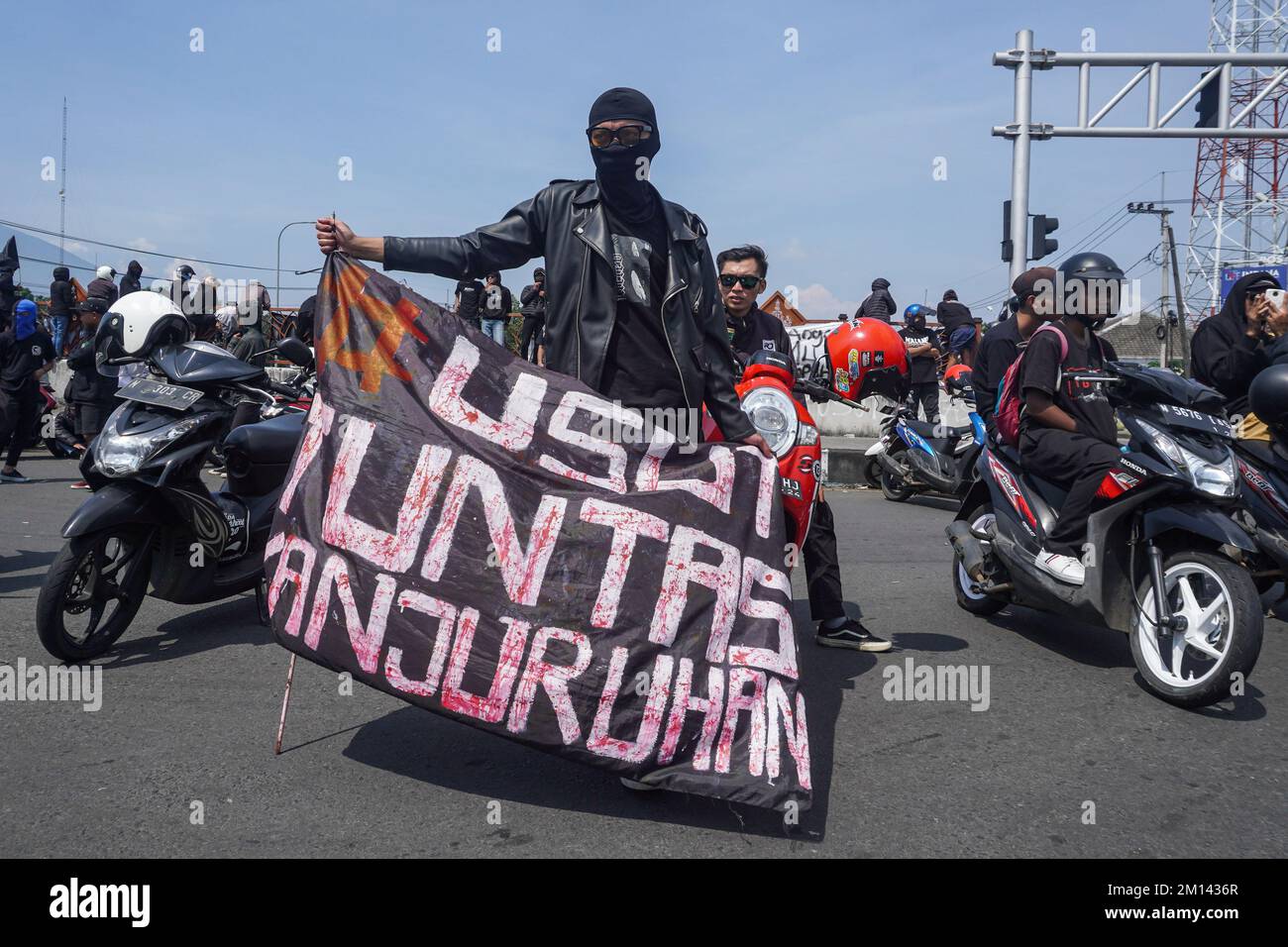 A demonstrator holds a banner with the words "Usut Tuntas Kanjuruhan ...