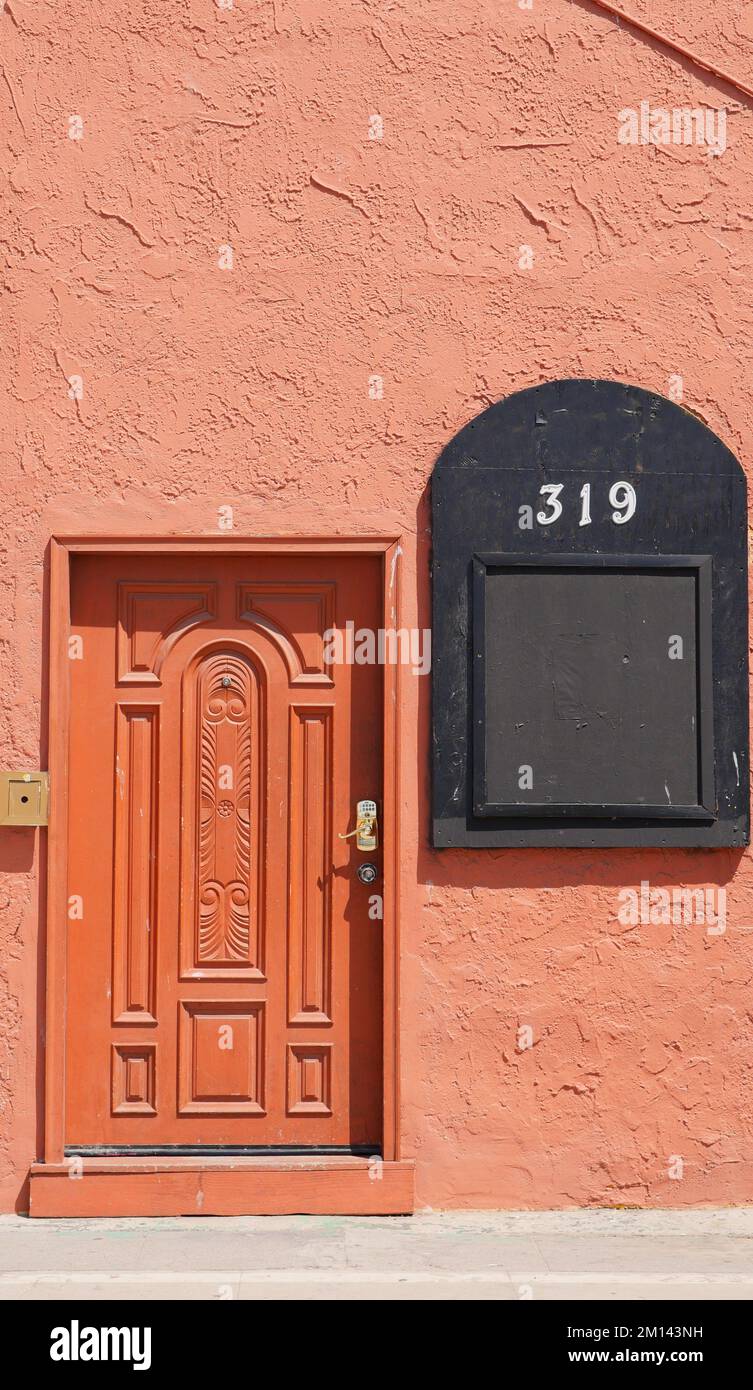 An organge building with its matching door next to a black board with ...