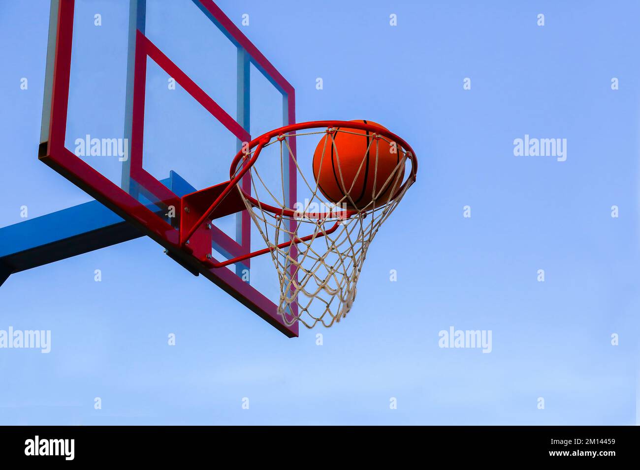 A basketball in a basket on an outdoor basketball court. A basketball ...