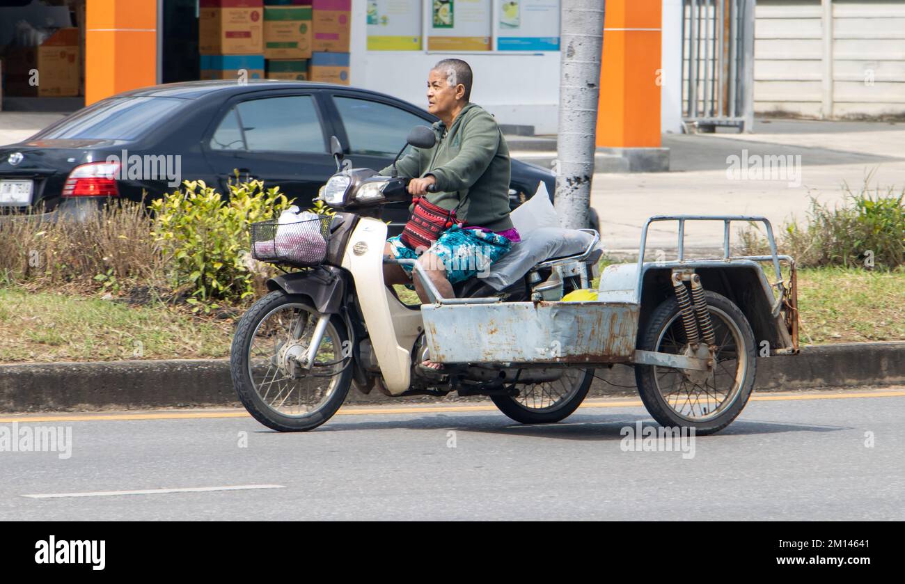 RATCHABURI, THAILAND, NOV 16 2022, A woman drives a motorcycle with an ...