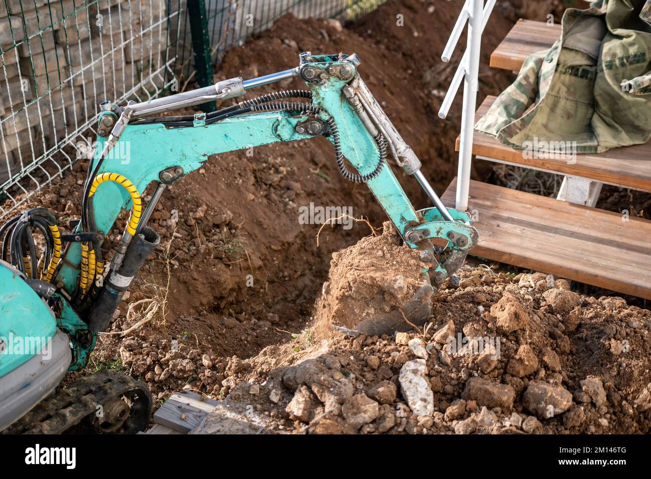 Mini excavator digs a trench to lay pipes. Close up of an excavator ...