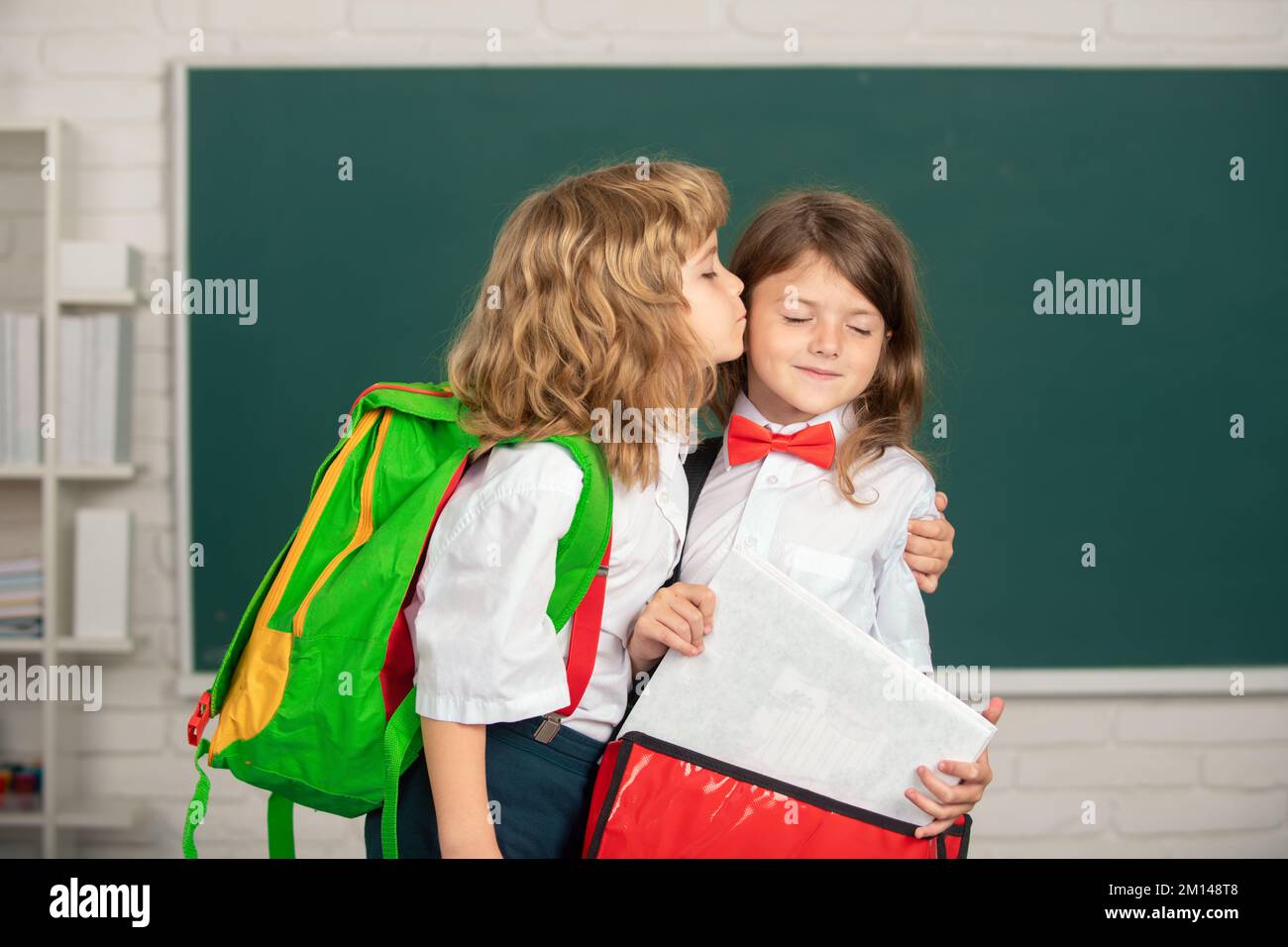School friends, hug and kiss. Portrait of two happy school kids ...