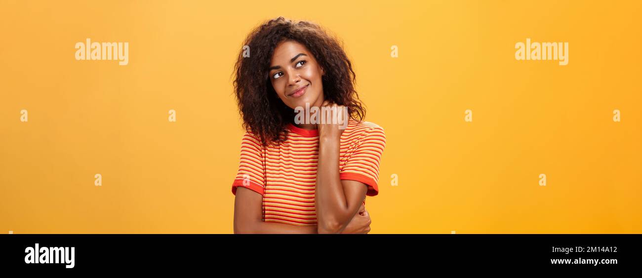Cute and gentle dreamy dark-skinned girl with cruly hairstyle tilting ...