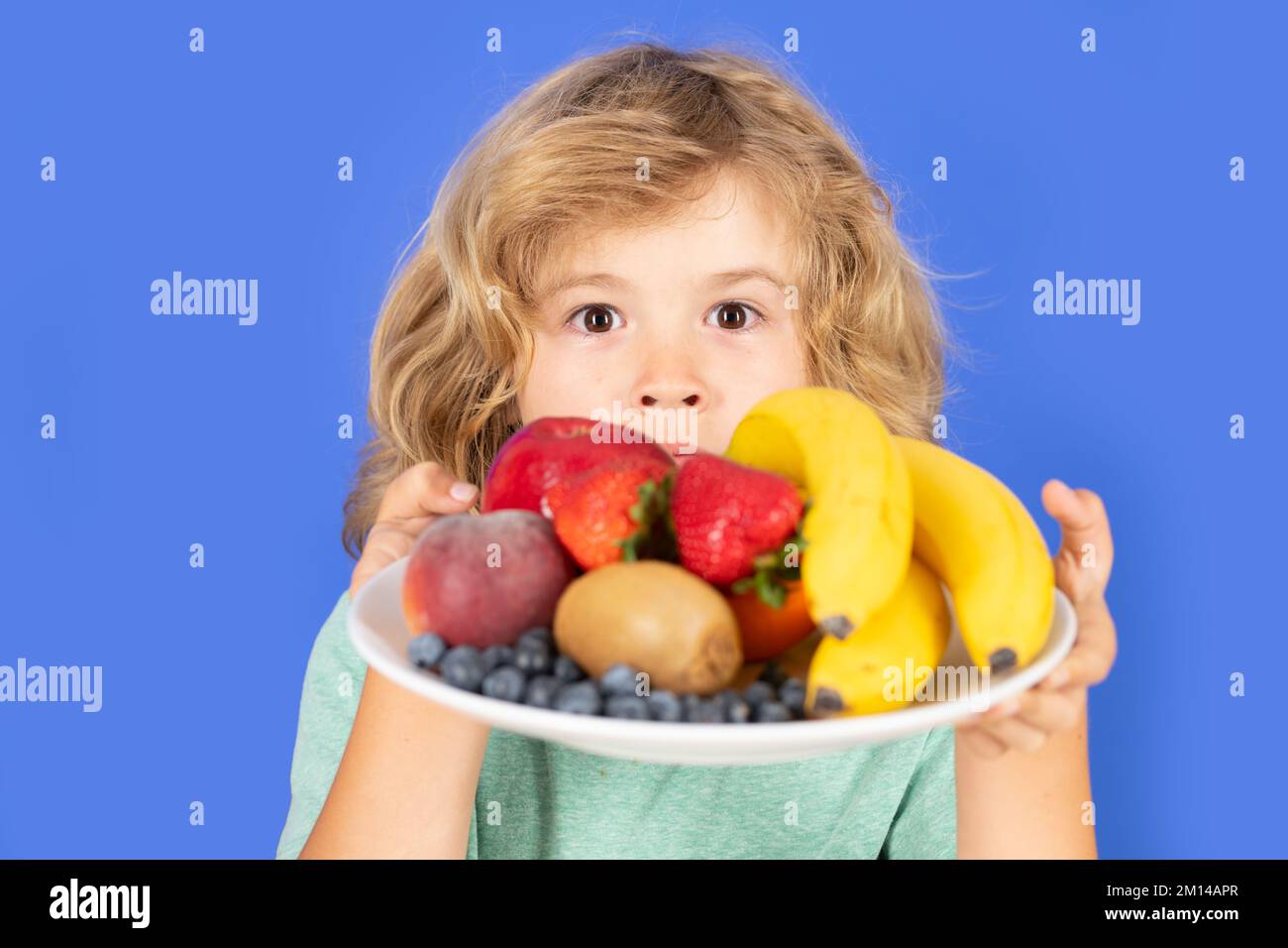 Funny child hold plate with fruits. Funny child eating fresh fruit ...