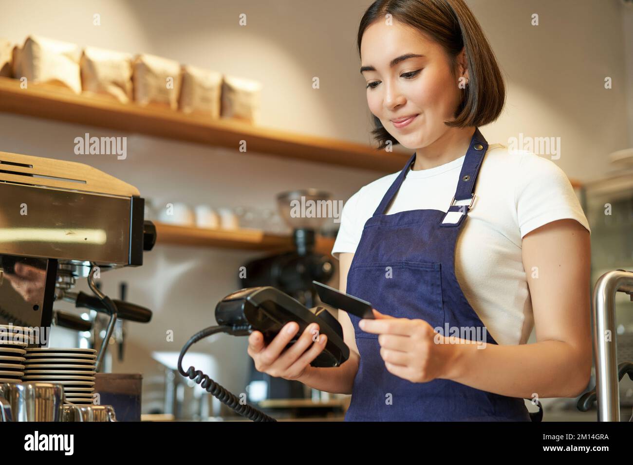 Cute asian girl, barista in cafe processing contactless payment, insert ...