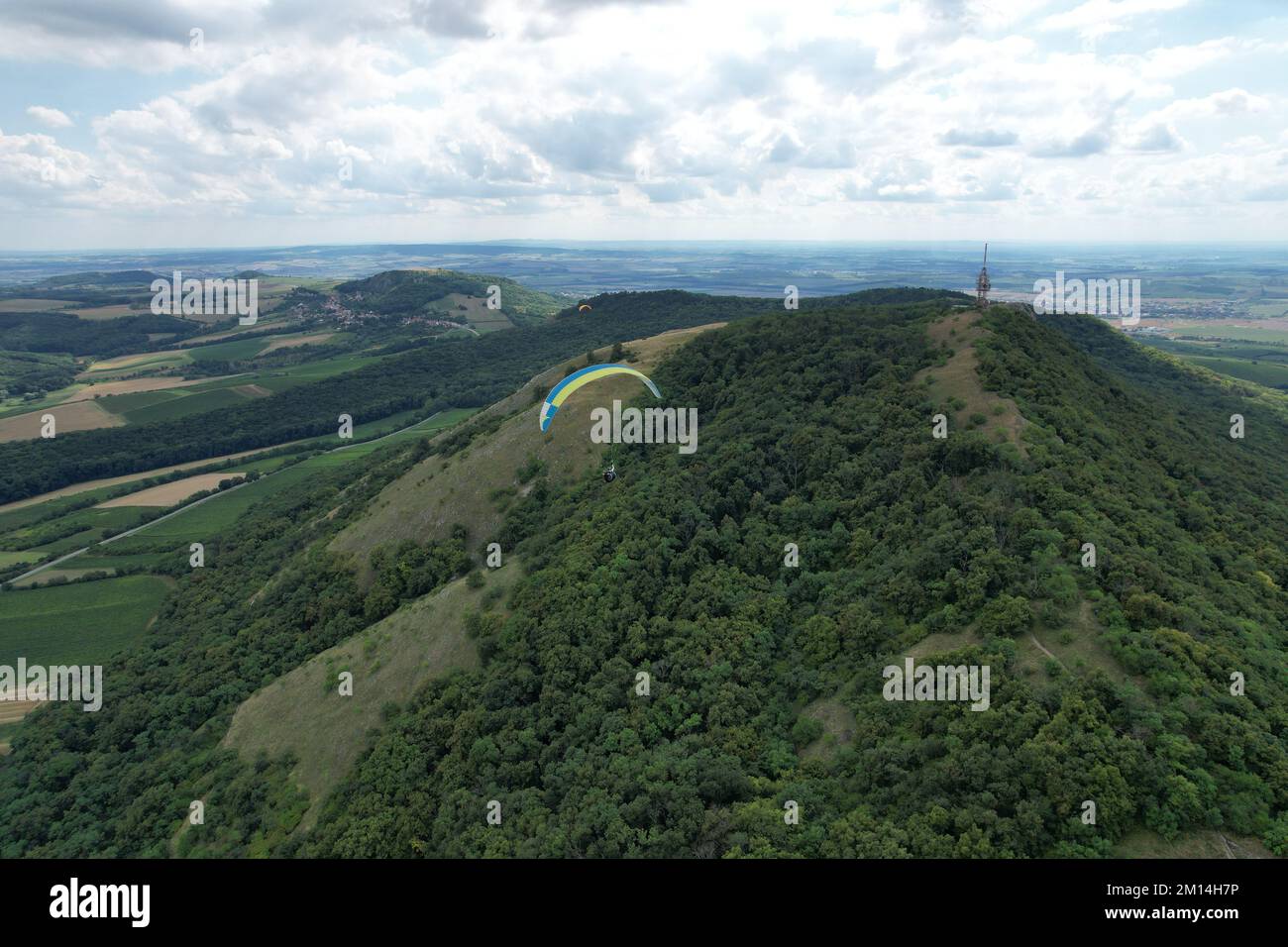 An aerial view of a person paragliding with a cloudy blue sky in the ...
