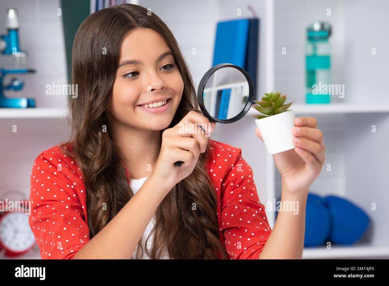 School girls with magnifying glass examining plants. Science or biology ...