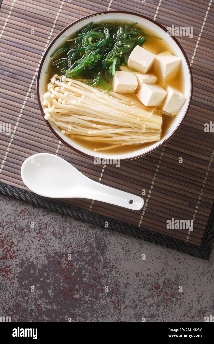 Japanese vegetarian shiro miso soup with tofu, enoki mushrooms, wakame seaweed close-up in a ...